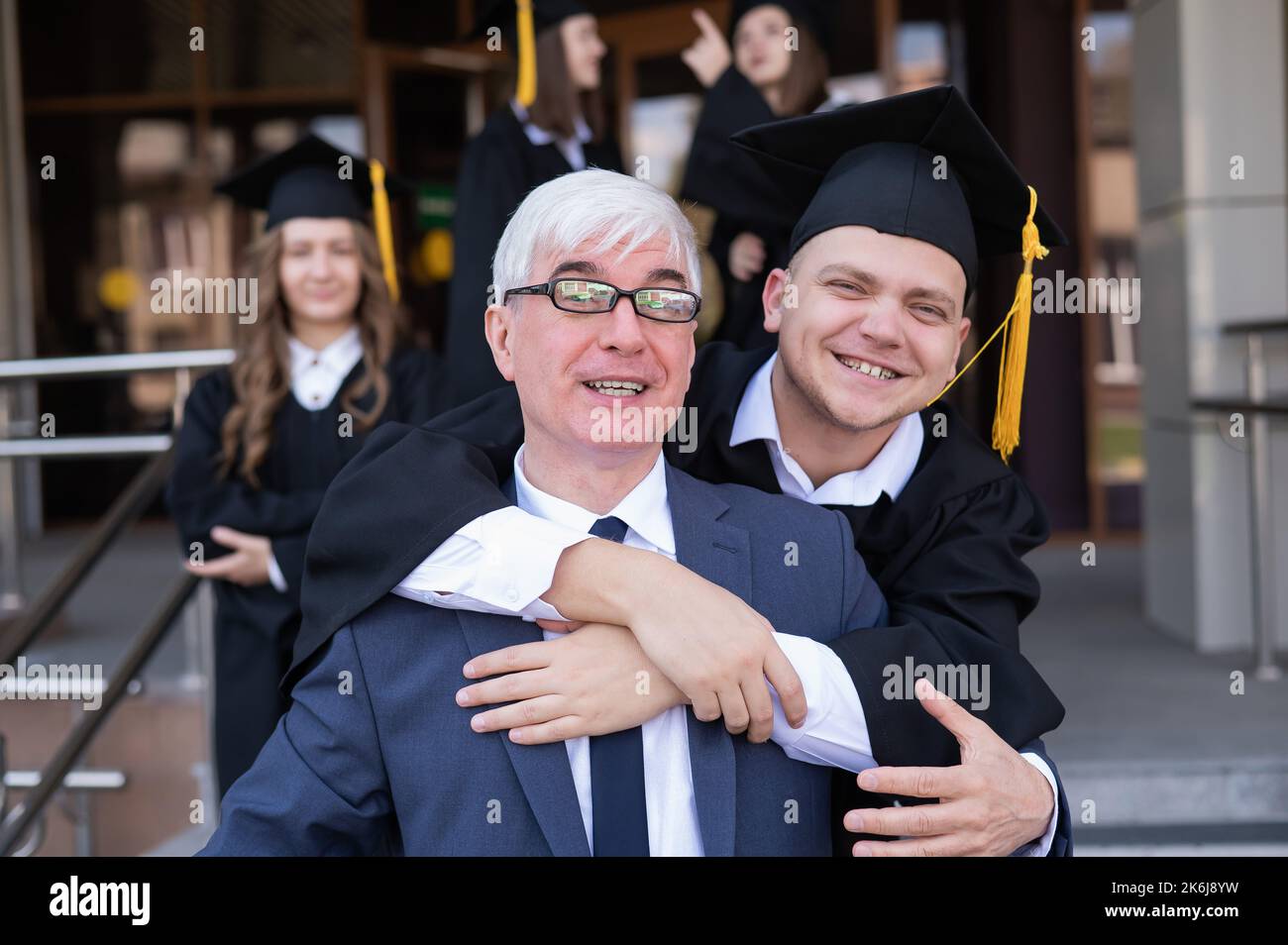 Father and son embrace at graduation. Parent congratulates university ...
