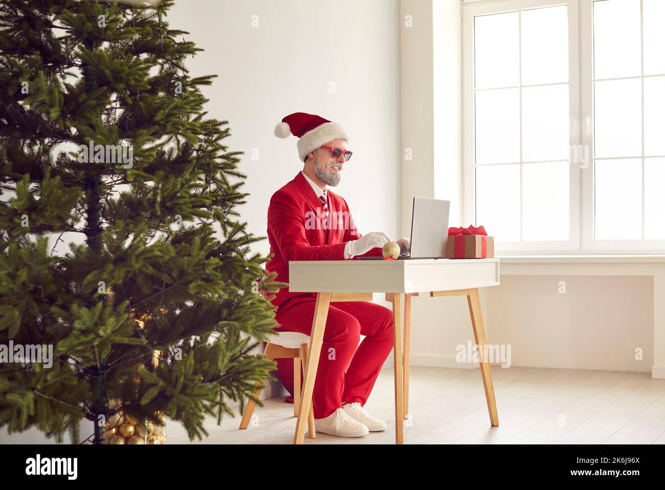 Funny man in Santa costume working on laptop computer in office with ...