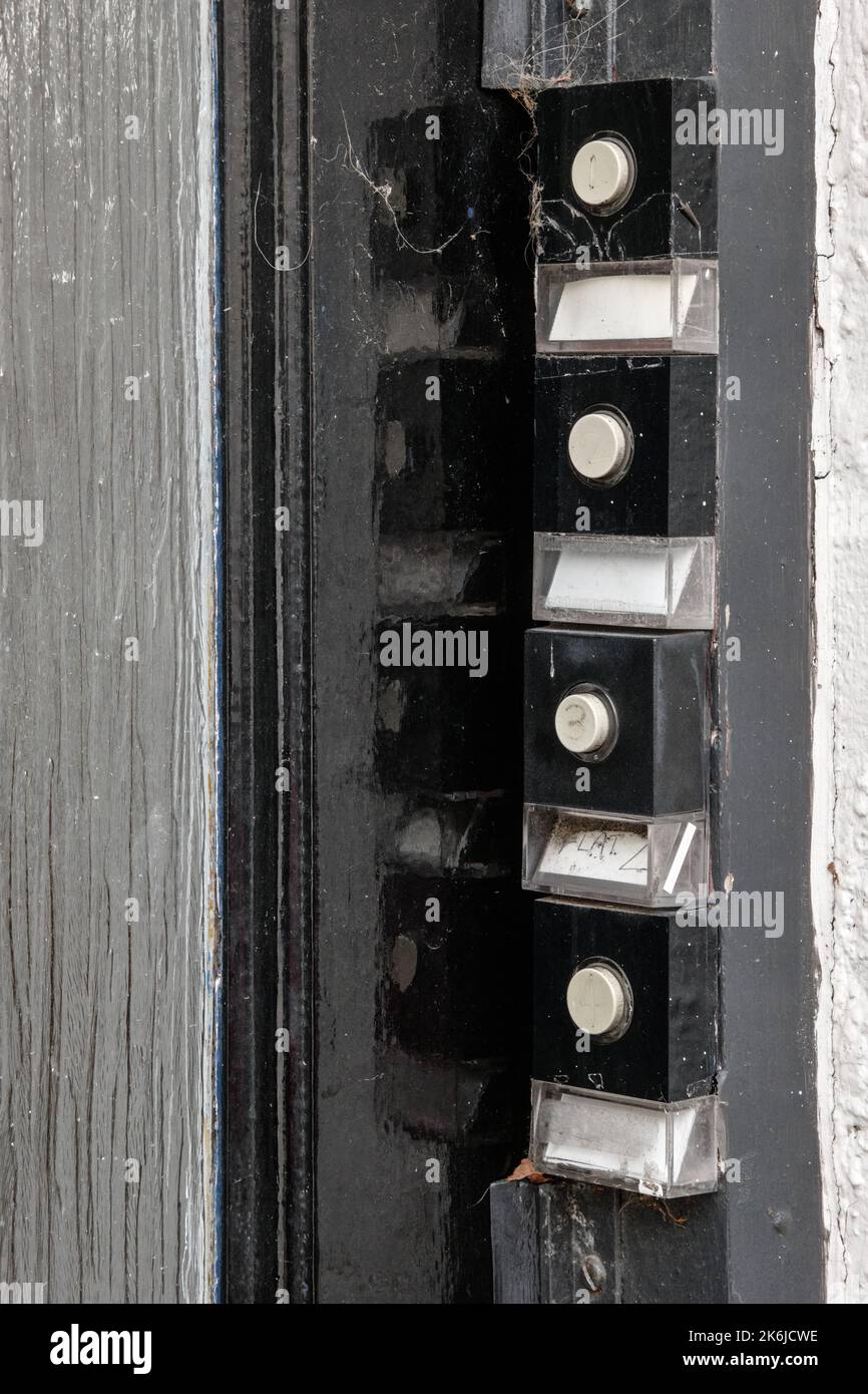 Set of four old black and white doorbells with name tags outside an ...