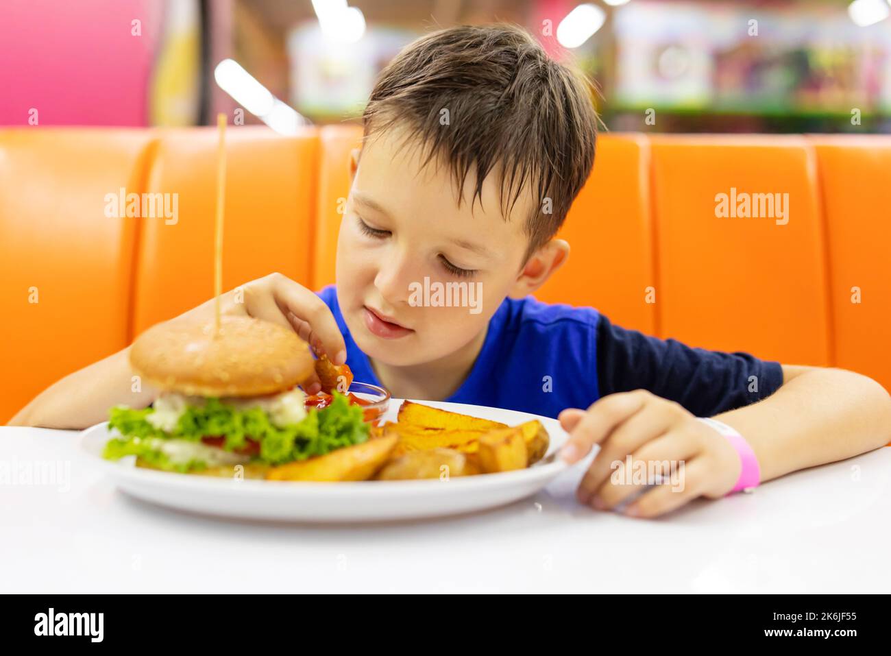 Child eating hamburger and French fries in a fast food restaurant Stock ...