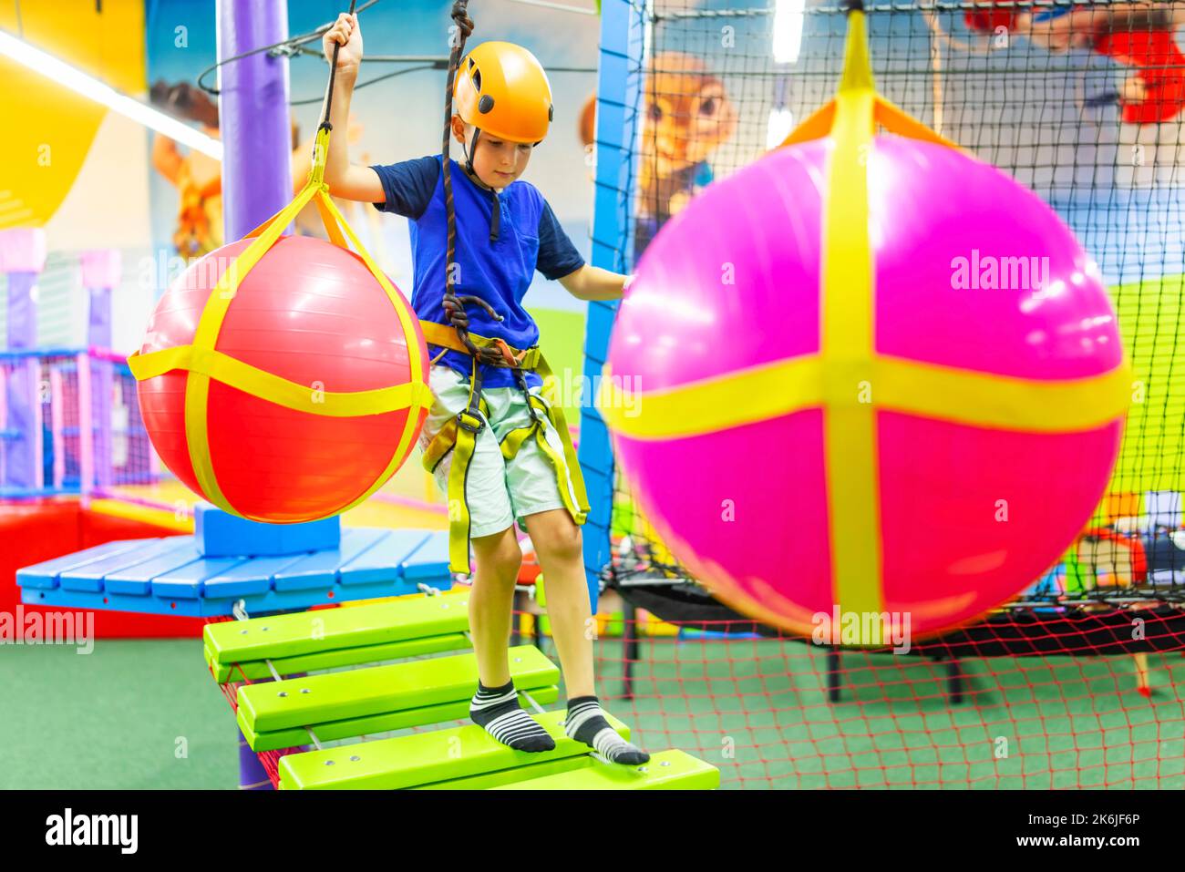 Boy in protective gear holding safety rope and passing obstacle course ...