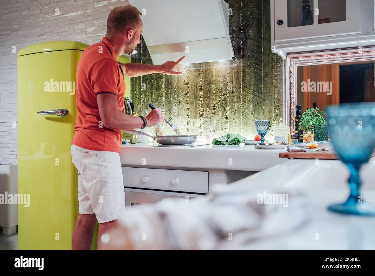 Middle-aged man cooking frying something delicious in the pan and ...