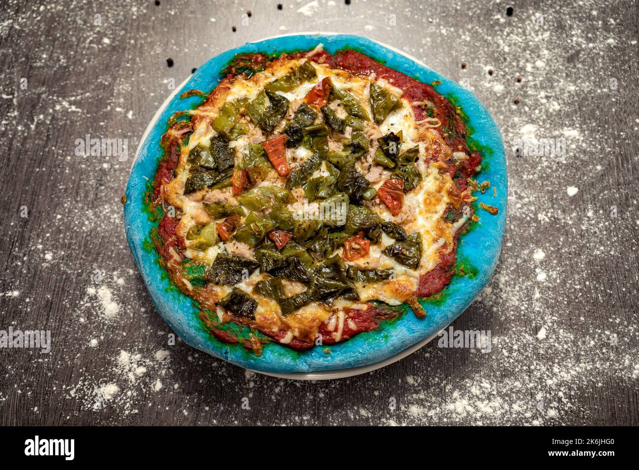 Baked pizza with tuna, green pepper and cheese, and blue dough. Healthy ...