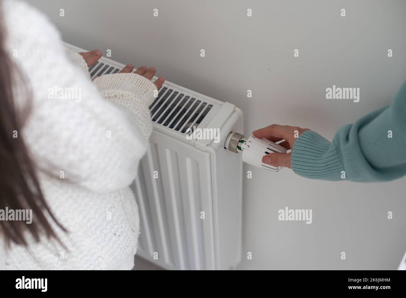 Child warming hands on heating radiator near white wall, closeup Stock ...