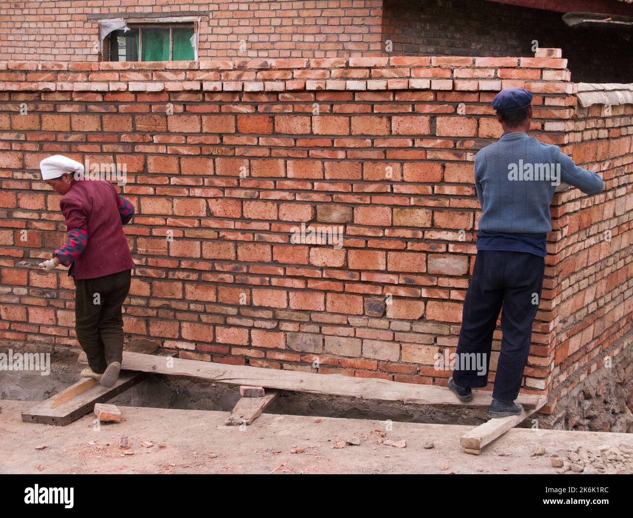New building / build wall of bricks being built by a male and female ...