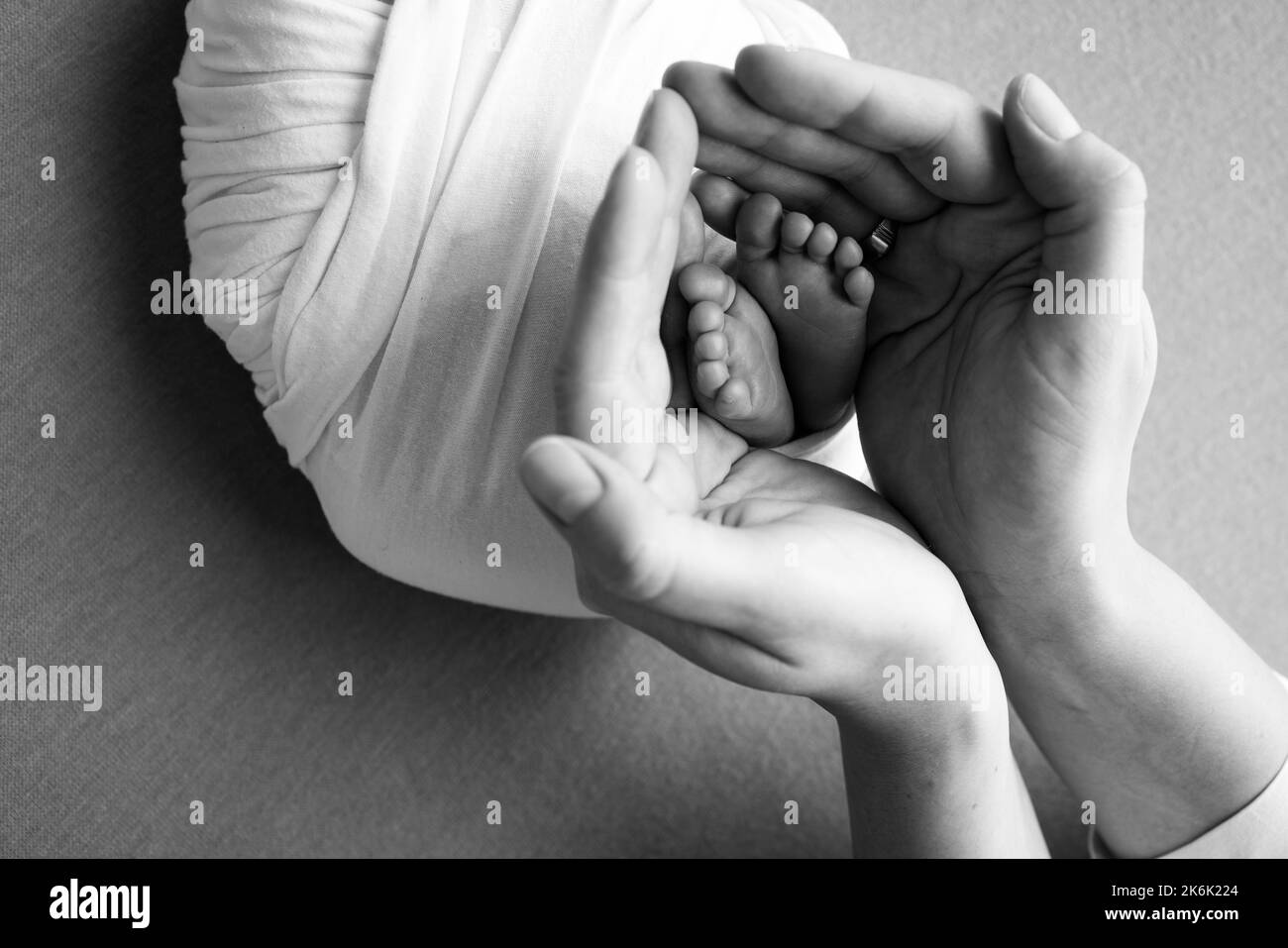 Father and mother hold the legs of a newborn baby. Feet of a newborn in ...