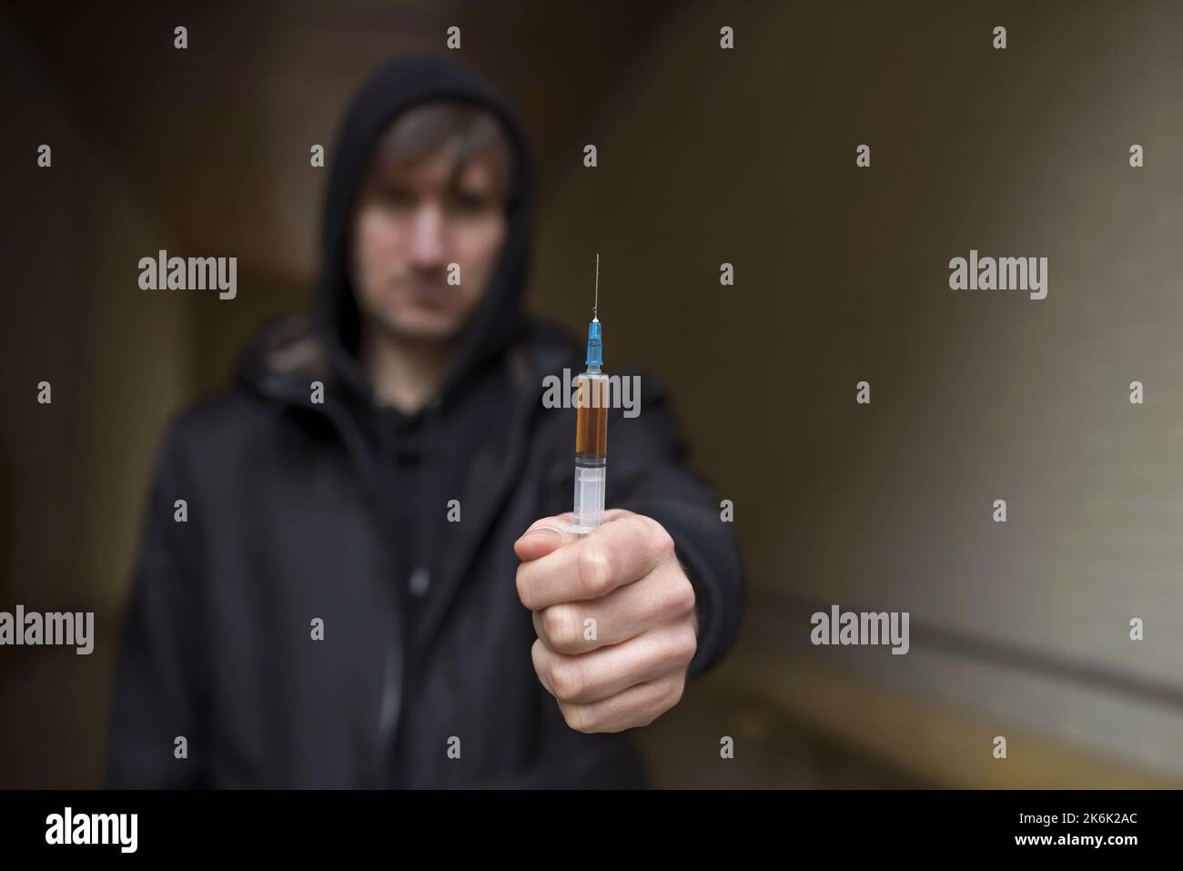 Addict holding a syringe in his hand on the street. Addiction Concept ...