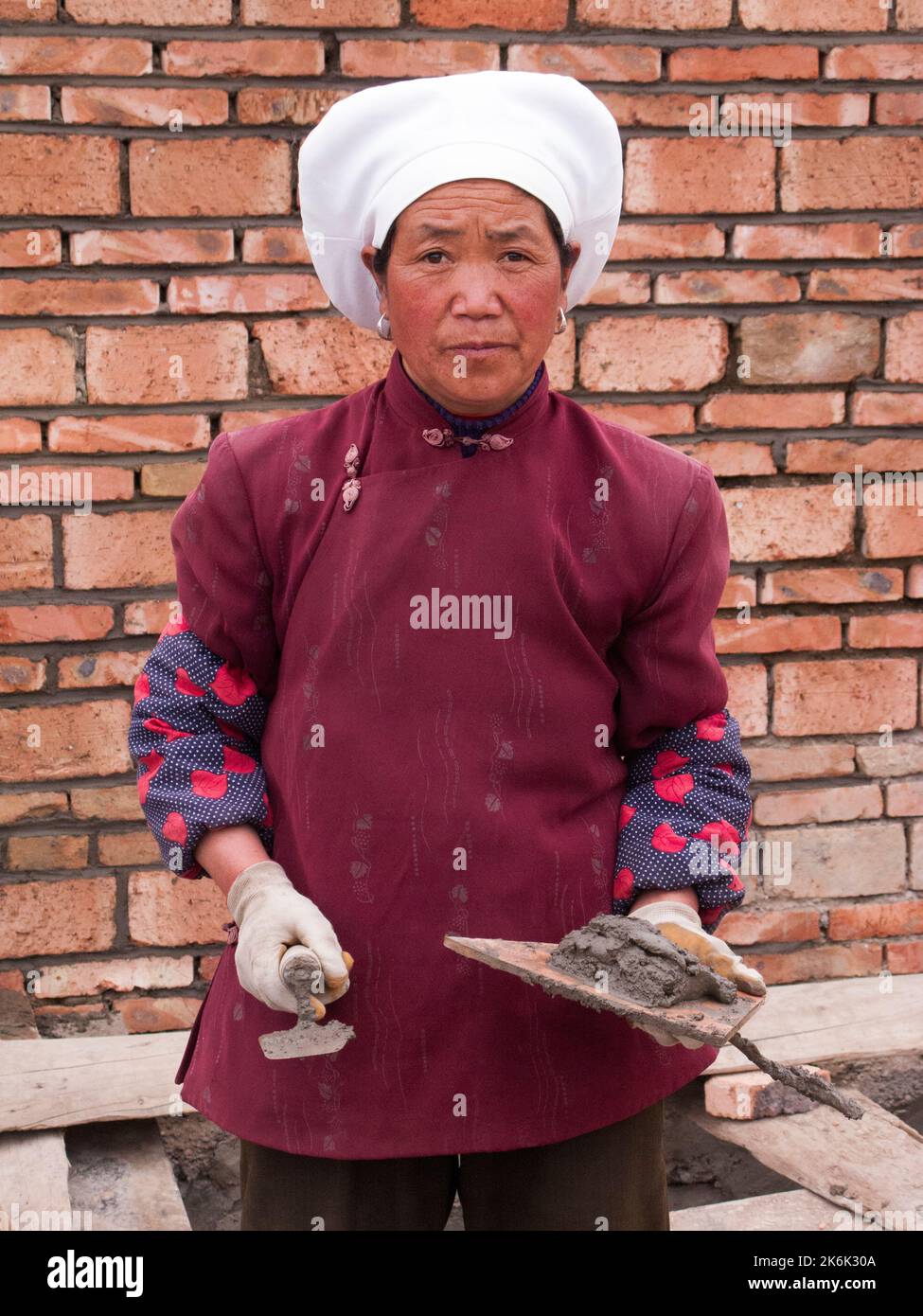 Woman / female brick layer laying the bricks of a building / builds the ...