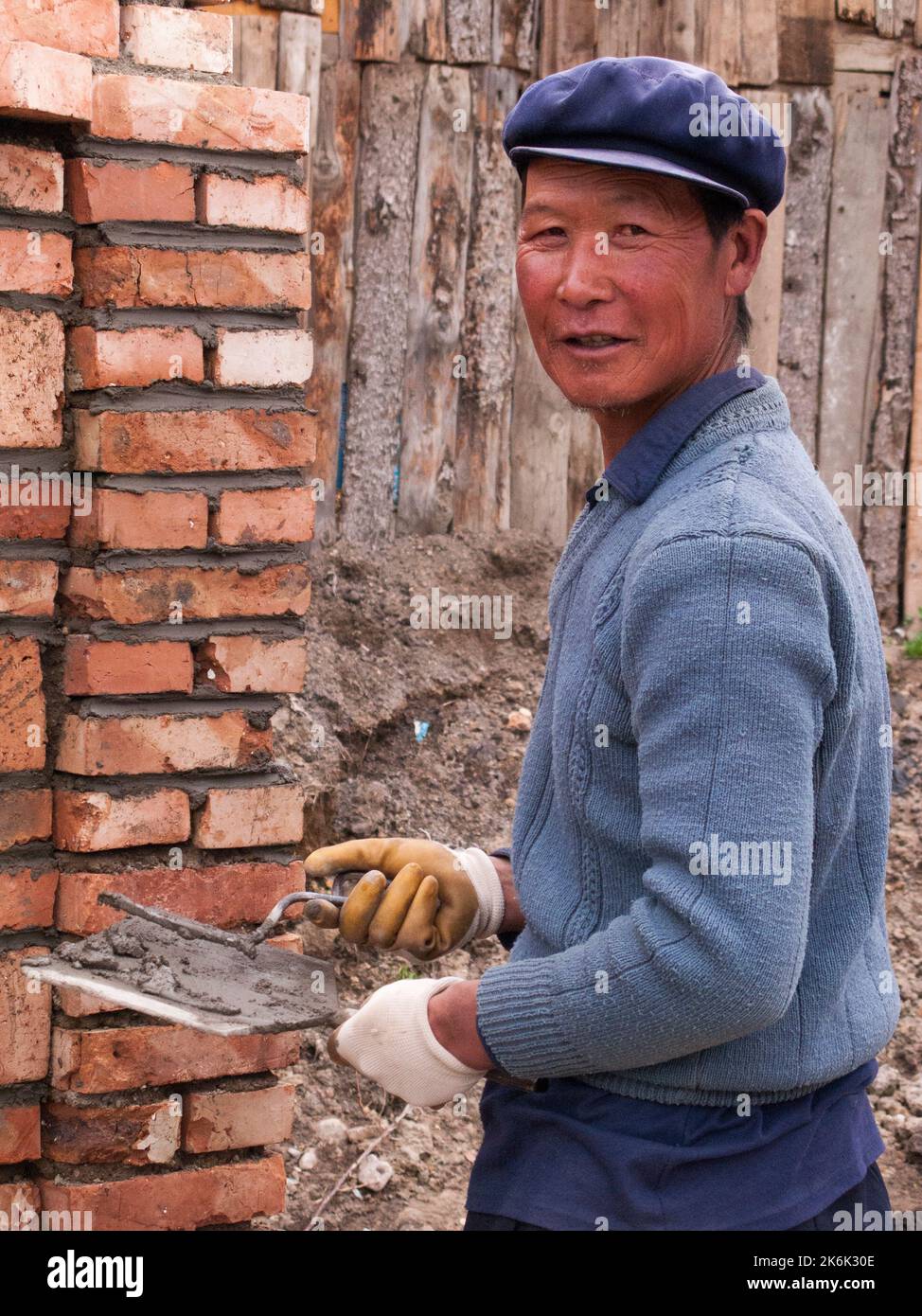 Man / male brick layer pointing after laying the bricks of a building ...