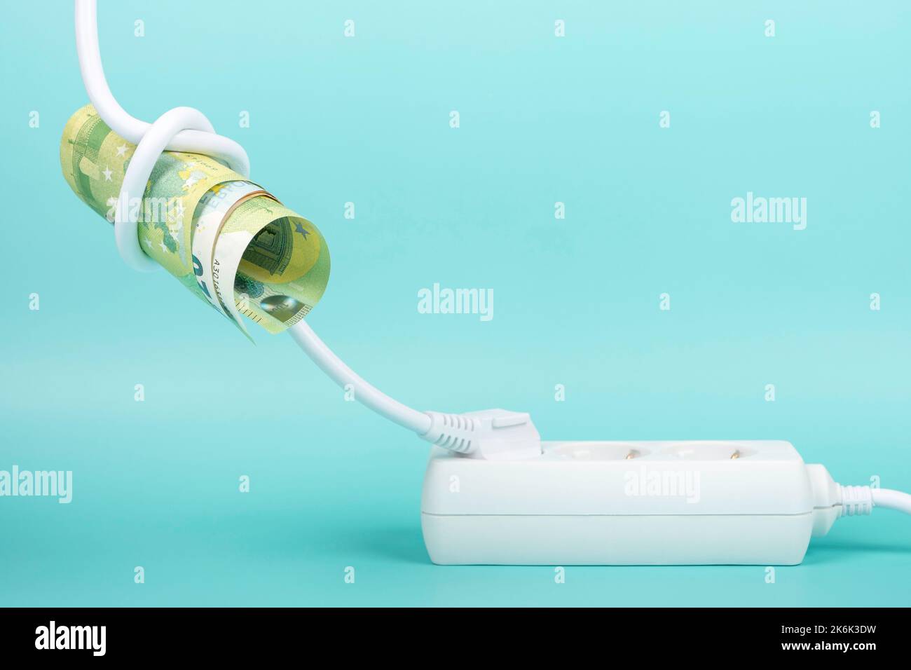 Euro banknote bills tied in knot in electrical power cable and plugged ...