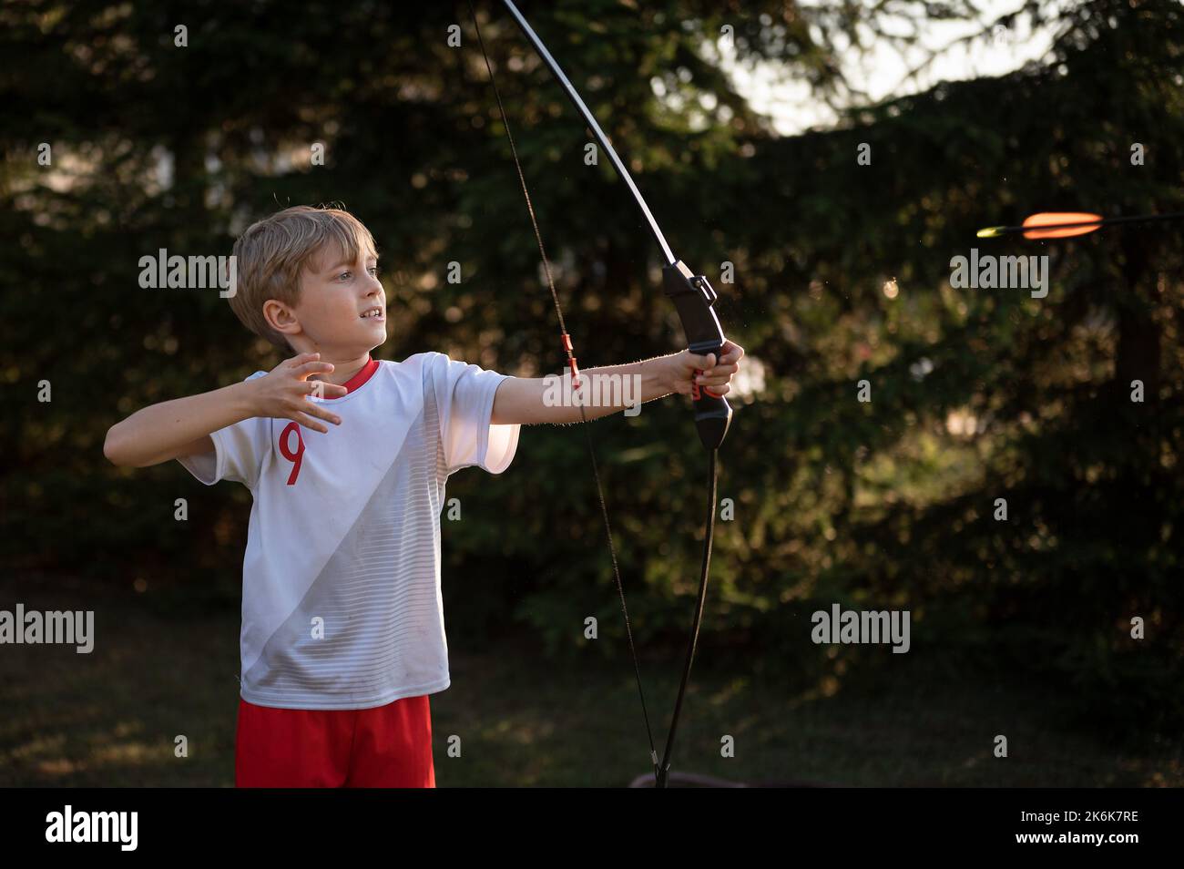 Young boy shoots a bow outdoor Stock Photo - Alamy