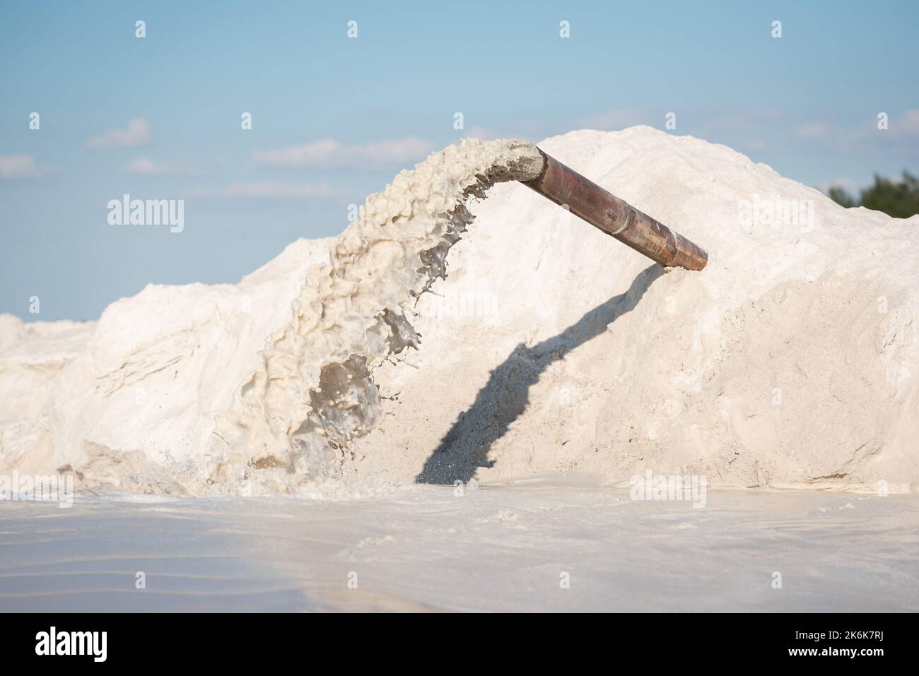 industrial wastewater flows out of a steel pipe in the sand into the ...