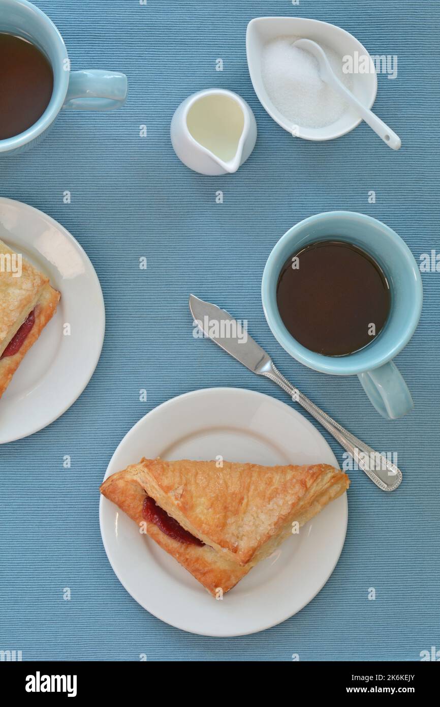 Fresh baked raspberry turnovers with coffee in vertical flat lay format ...