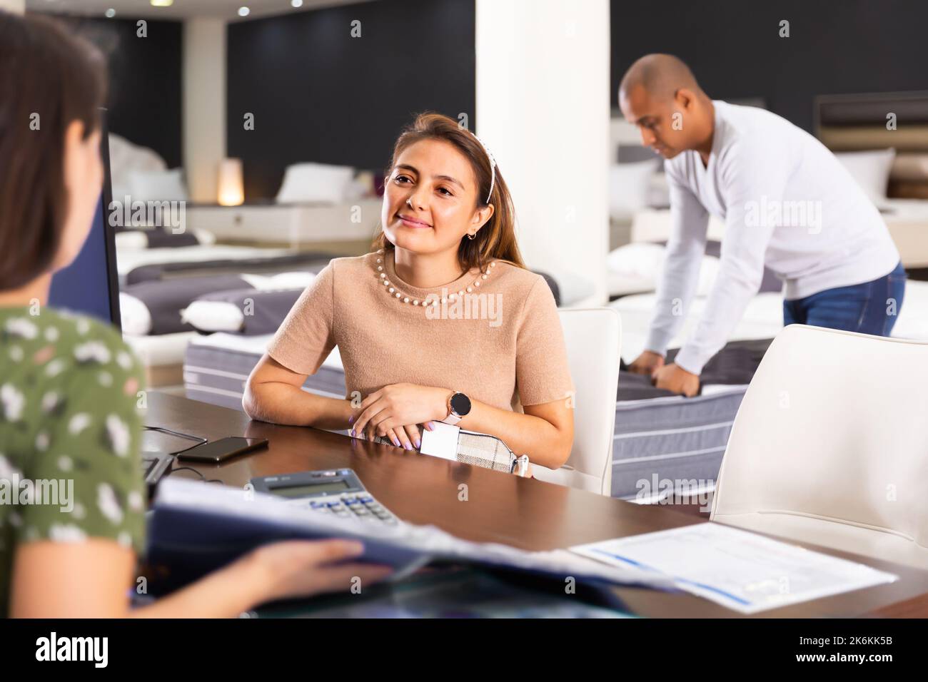 Polite seller showing variants of fabric Stock Photo - Alamy