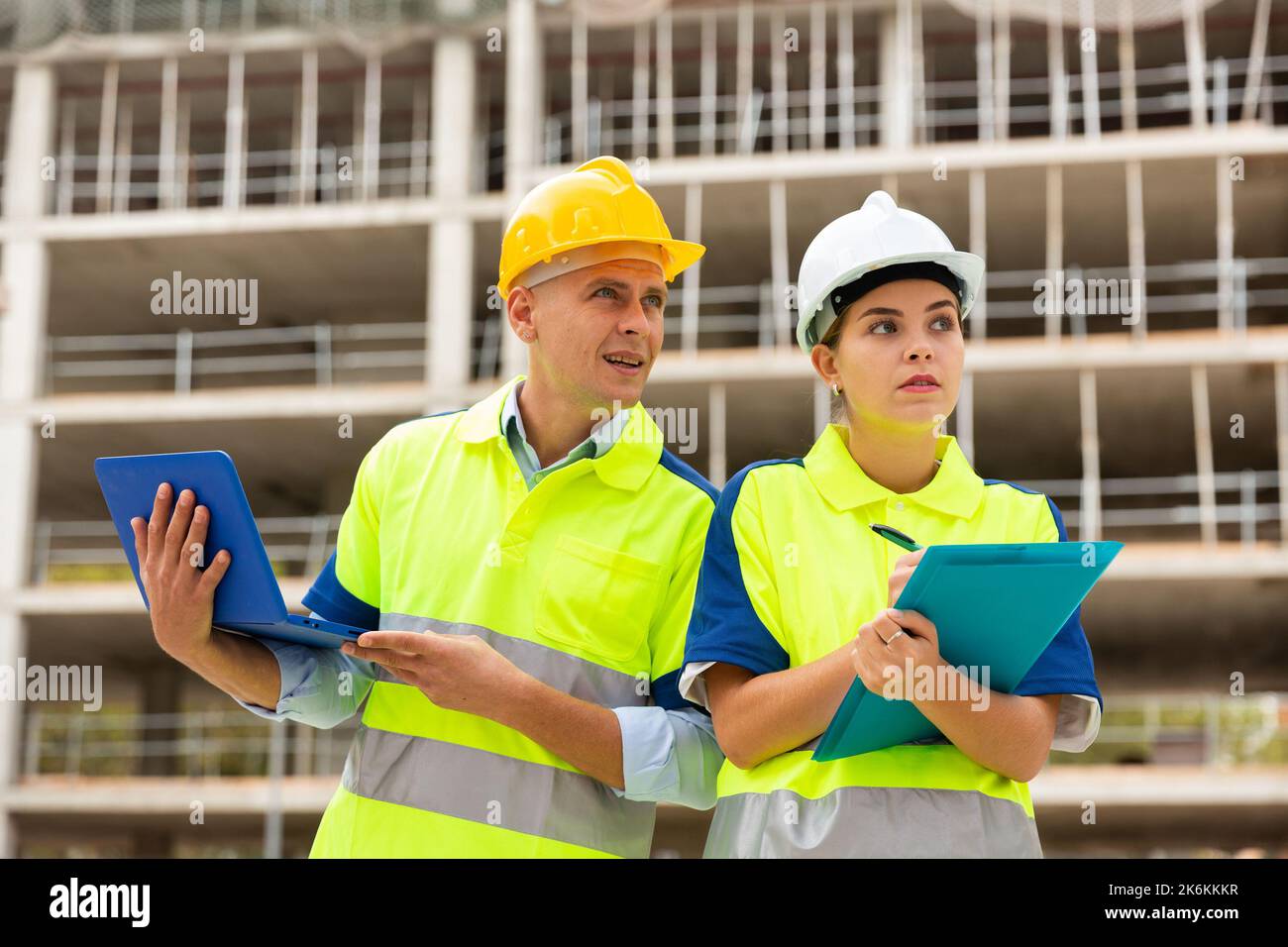 Two engineers are discussing an important project, holding a laptop and ...
