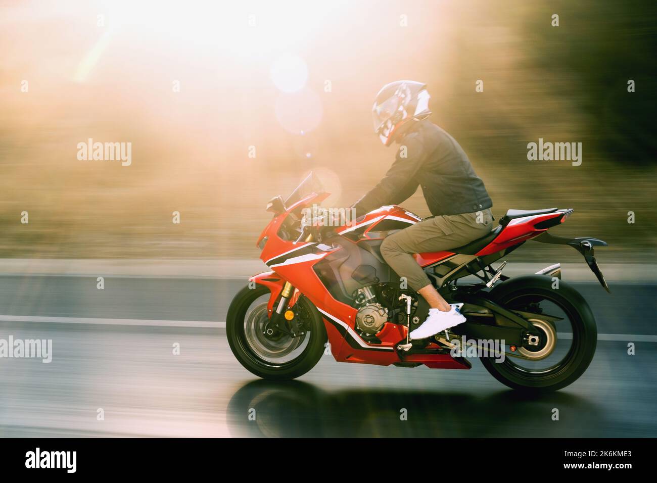 Side view of a motorcycle rider riding red race motorcycle on the ...