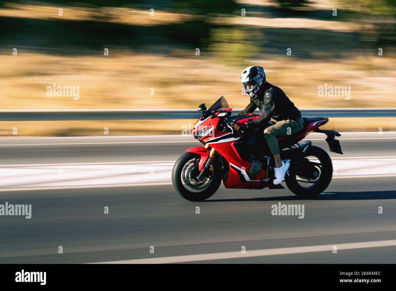 Side view of a motorcycle rider riding red race motorcycle on the ...