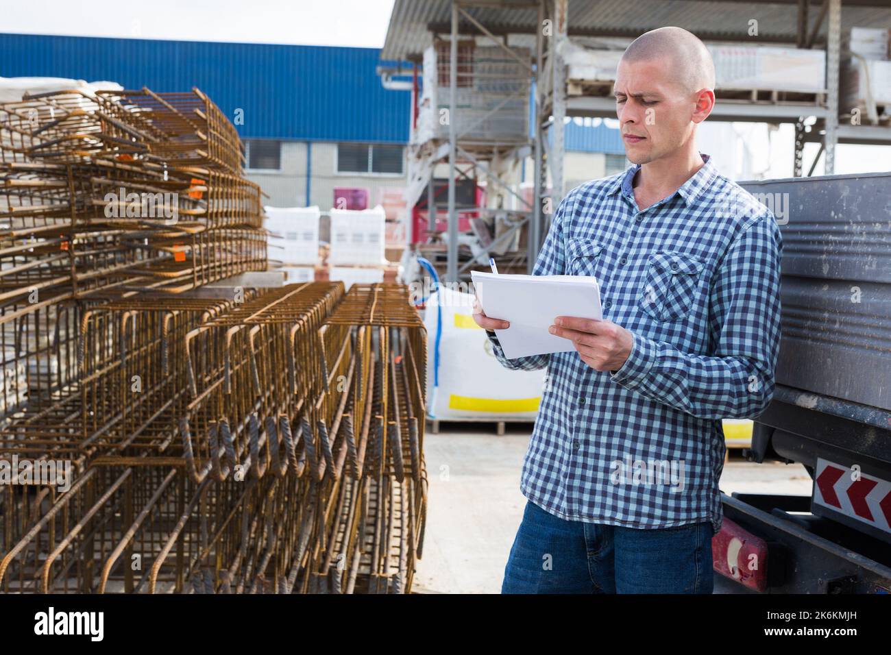 Construction shop worker prepares metal rebar for loading onto truck ...