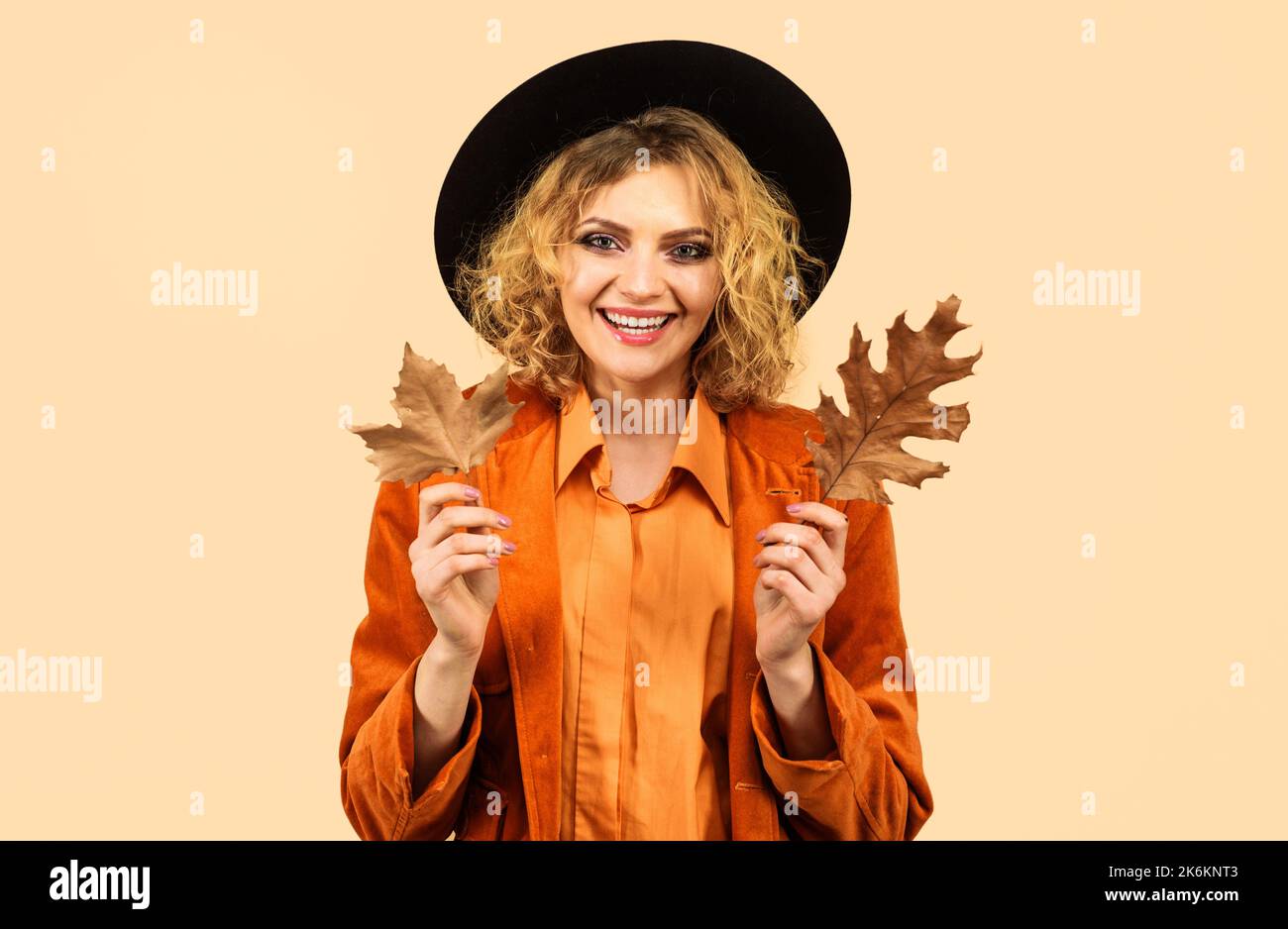Autumn fashion model. Smiling girl with yellow leaves. Woman in black ...