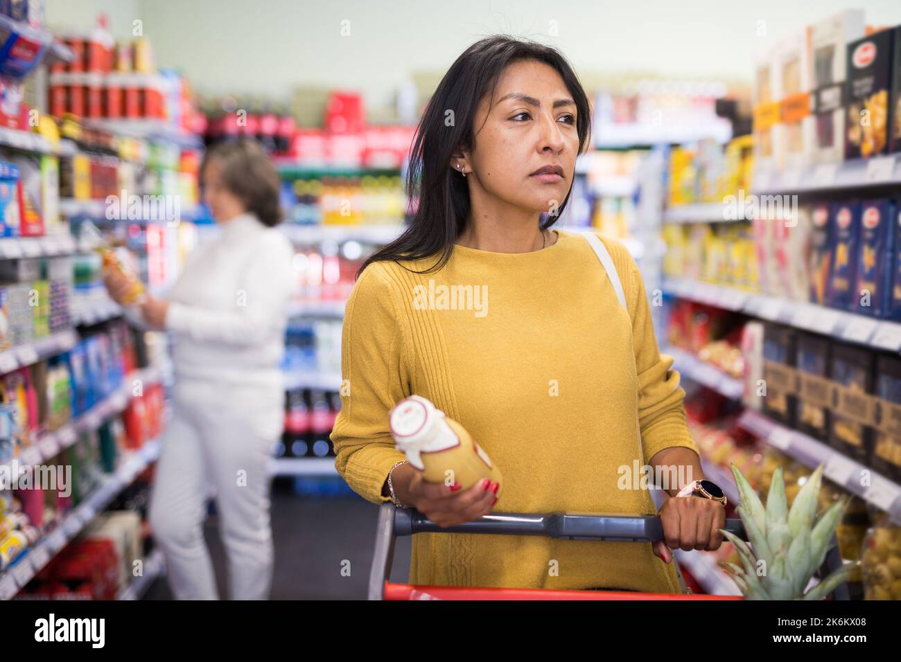 Hispanic woman walking with shopping trolley in grocery shop Stock ...
