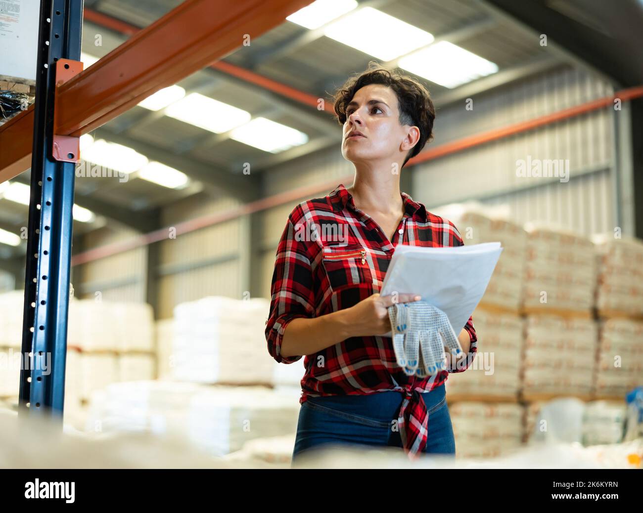 Female storekeeper checks availability of goods with documents in the ...