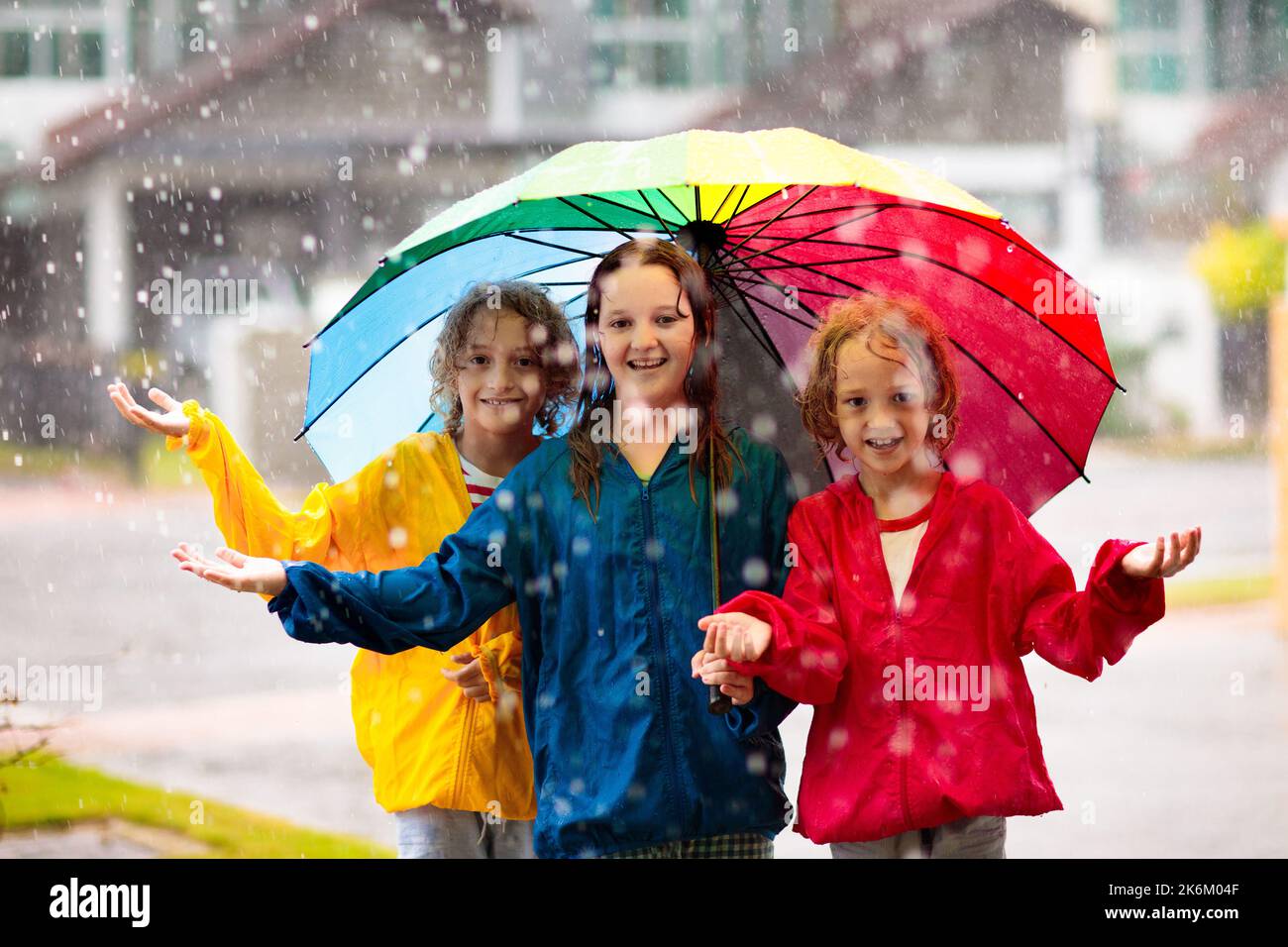 Kids play in heavy autumn rain. Children walk on city street in cold ...