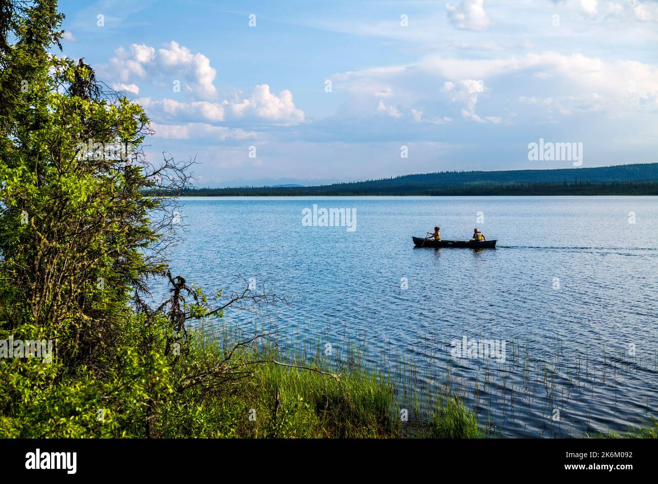 Two adults paddle a canoe at sunset across Deadman Lake; Deadman Lake ...