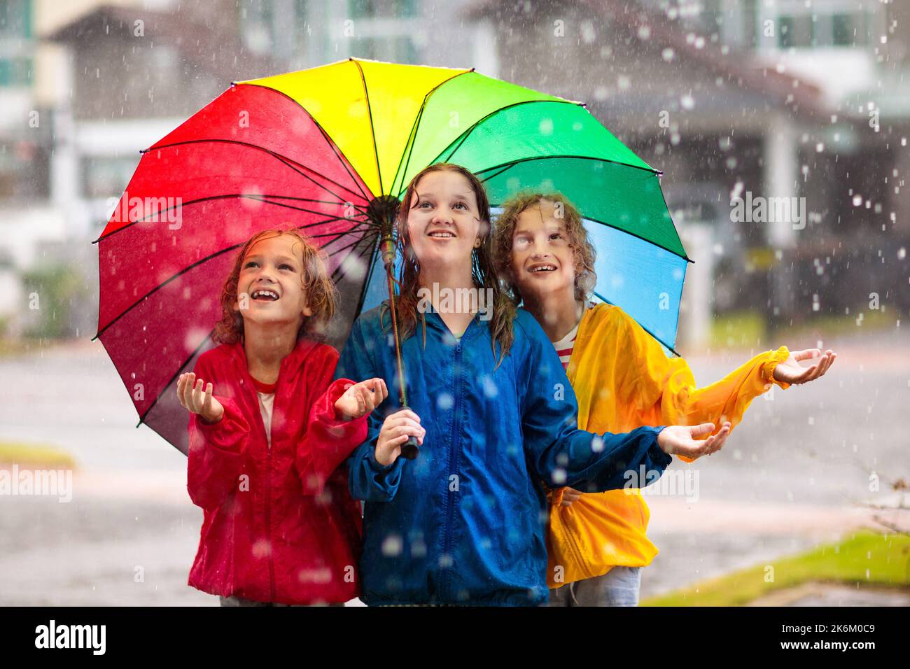Kids play in heavy autumn rain. Children walk on city street in cold ...