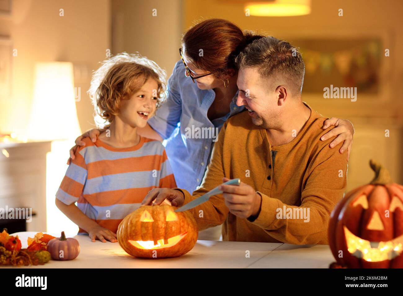 Family with kids carving pumpkin. Halloween trick or treat. Parents and ...