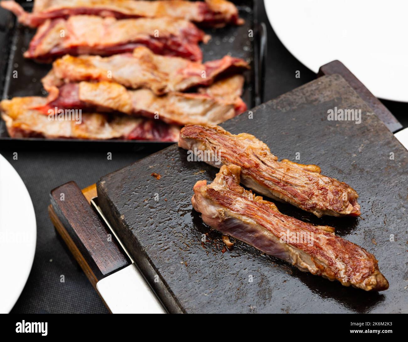Process of meat cooking on grilling stone Stock Photo - Alamy