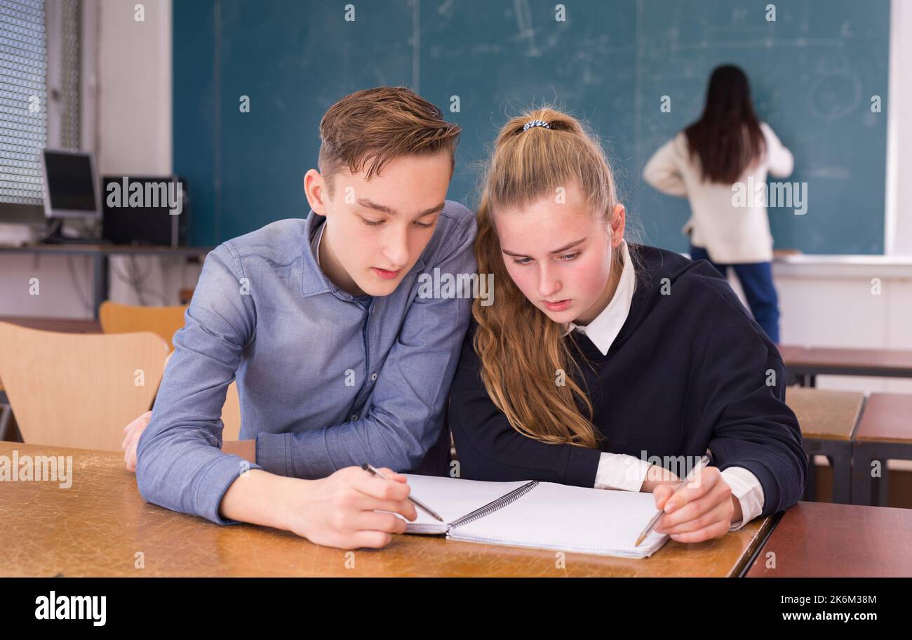 Young guy and girl students doing lesson in classroom Stock Photo - Alamy
