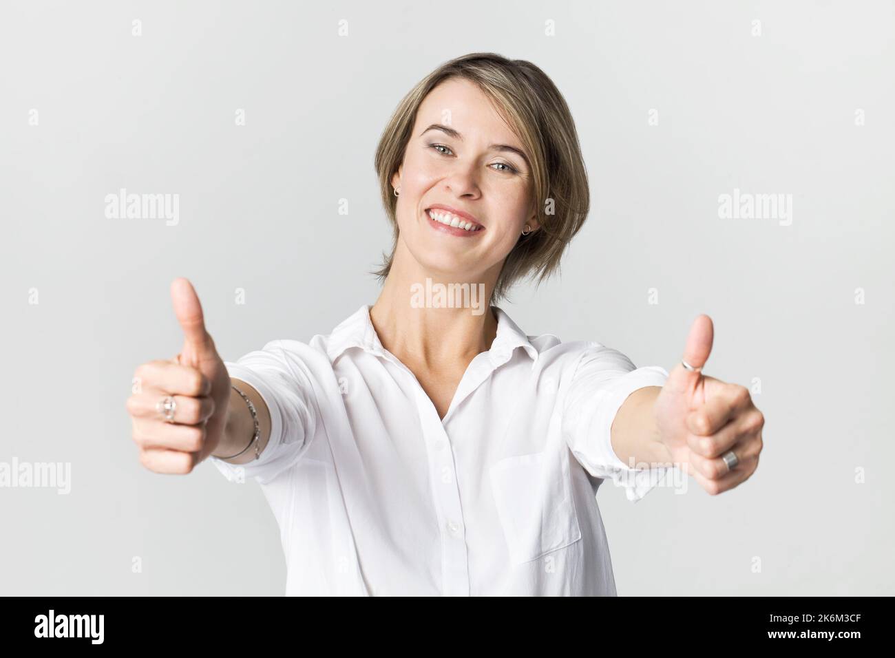 Happy young woman smiling against white background, OK gesture Stock ...