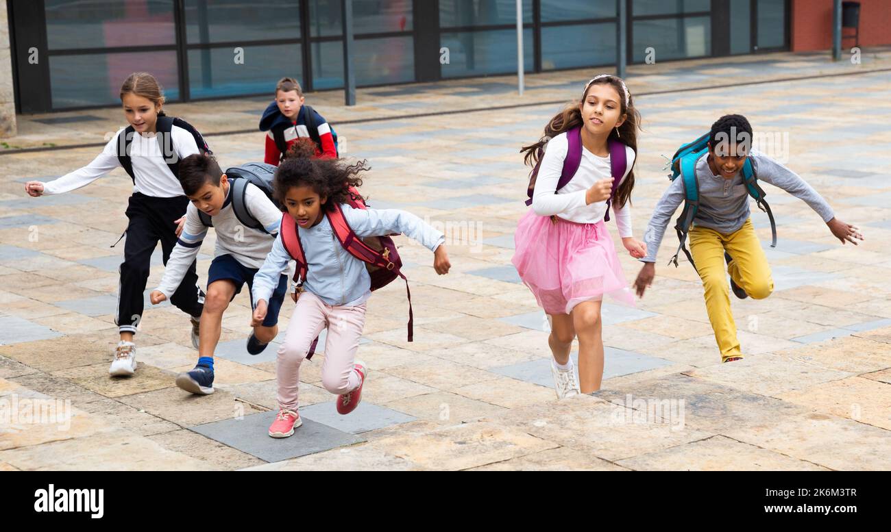 Tween boys and girls with school backpacks running in schoolyard Stock ...