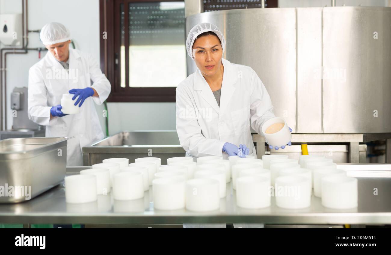 Woman wearing uniform showing cottage cheese production process on ...