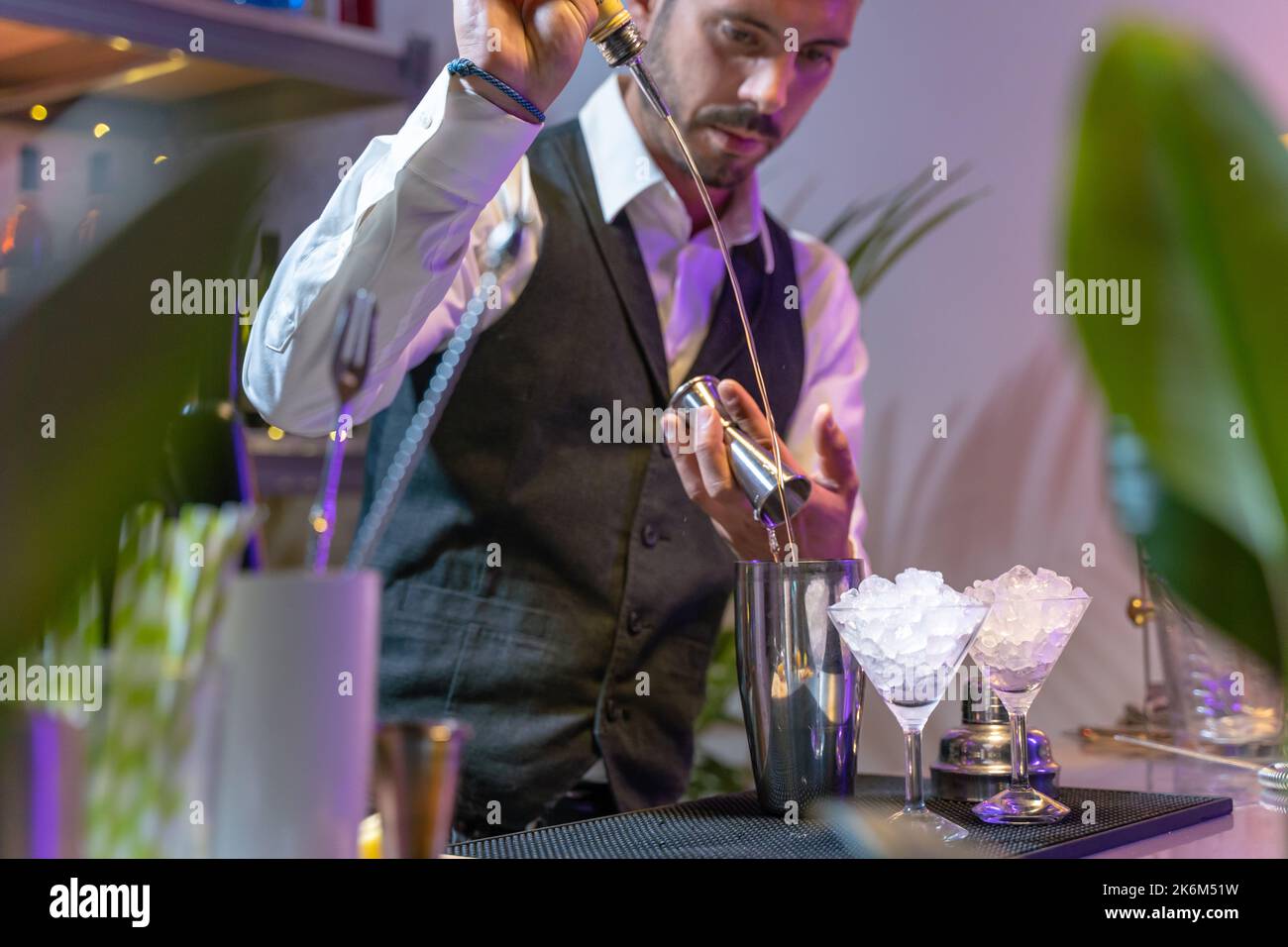 Barman pouring cocktail Mojito in night club adding ingredients and ...