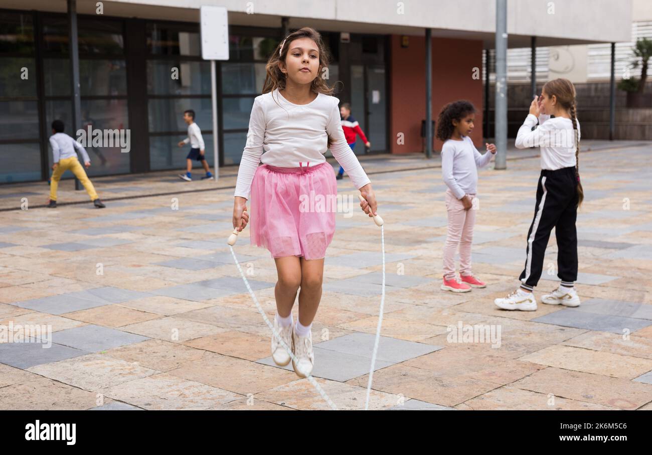 Tween girl in pink skirt jumping rope in schoolyard during recess Stock ...