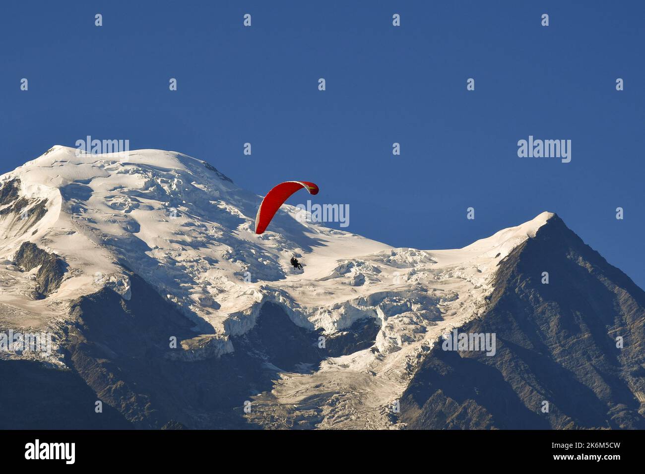A red paraglider flying in front of Mont Blanc mountain in the French ...