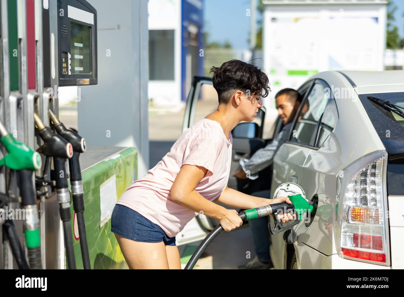 Latin woman filling up tank of her car with gasoline in gas station ...