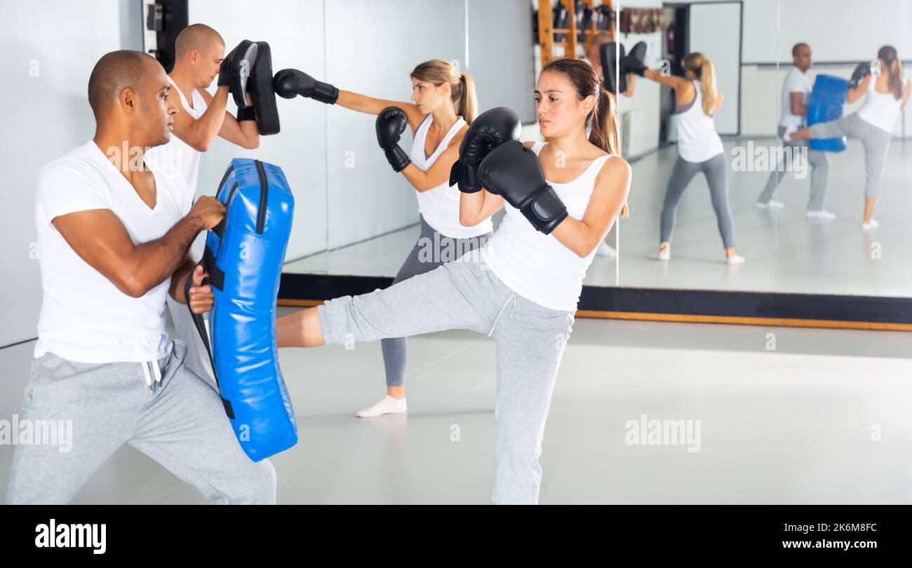 Woman kicking boxing shield in coach hands Stock Photo - Alamy