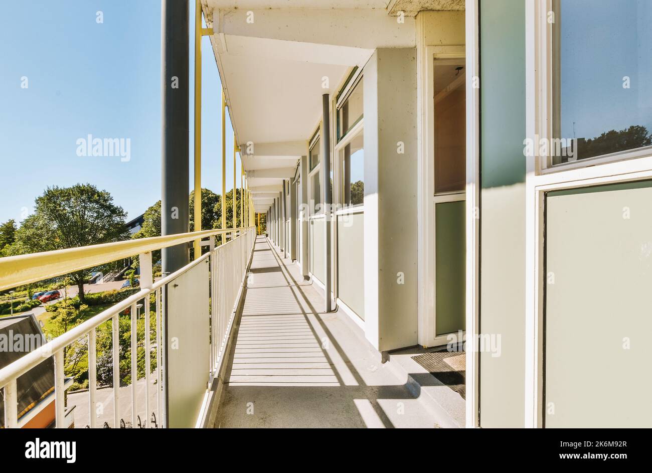 Narrow light corridor with doors of rooms illuminated with lamps inside ...
