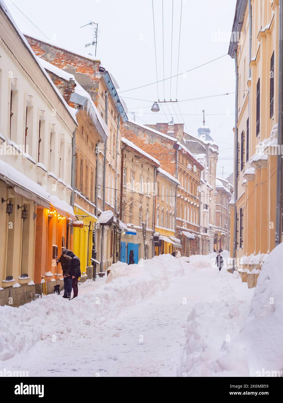 Snow covered street of Lviv old town with cafes and restaurants, car in ...