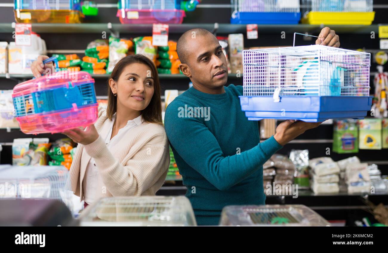 Man helping woman to choose hamster cage at store Stock Photo - Alamy