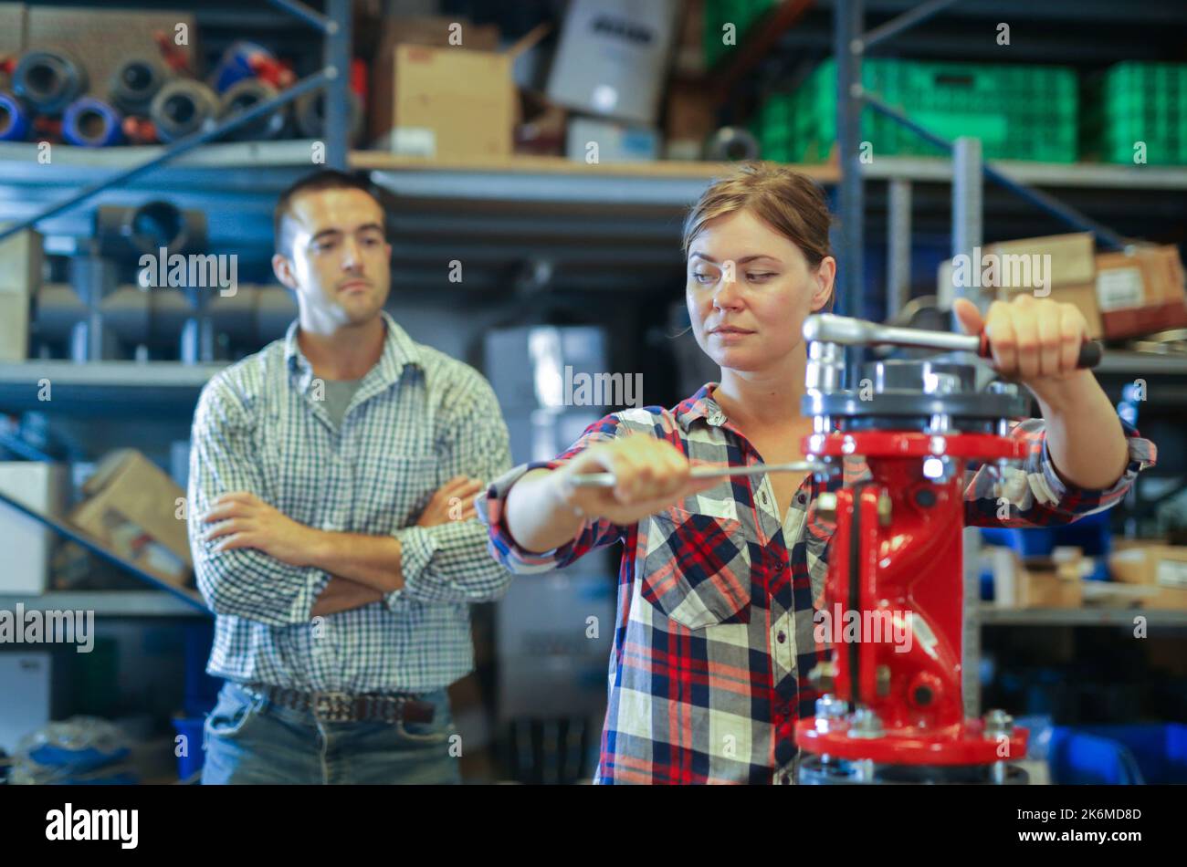 Female worker manually assembles shut-off valves under the guidance and ...