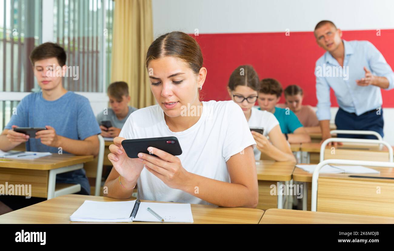 Pupils with smartphones sitting in class Stock Photo - Alamy
