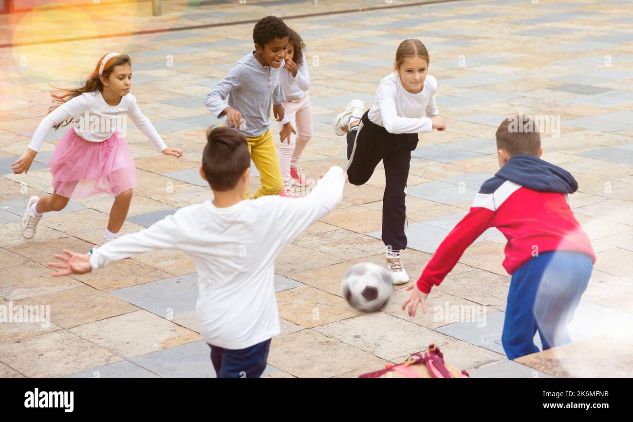 Group of tweenagers playing football in school yard after lessons Stock ...