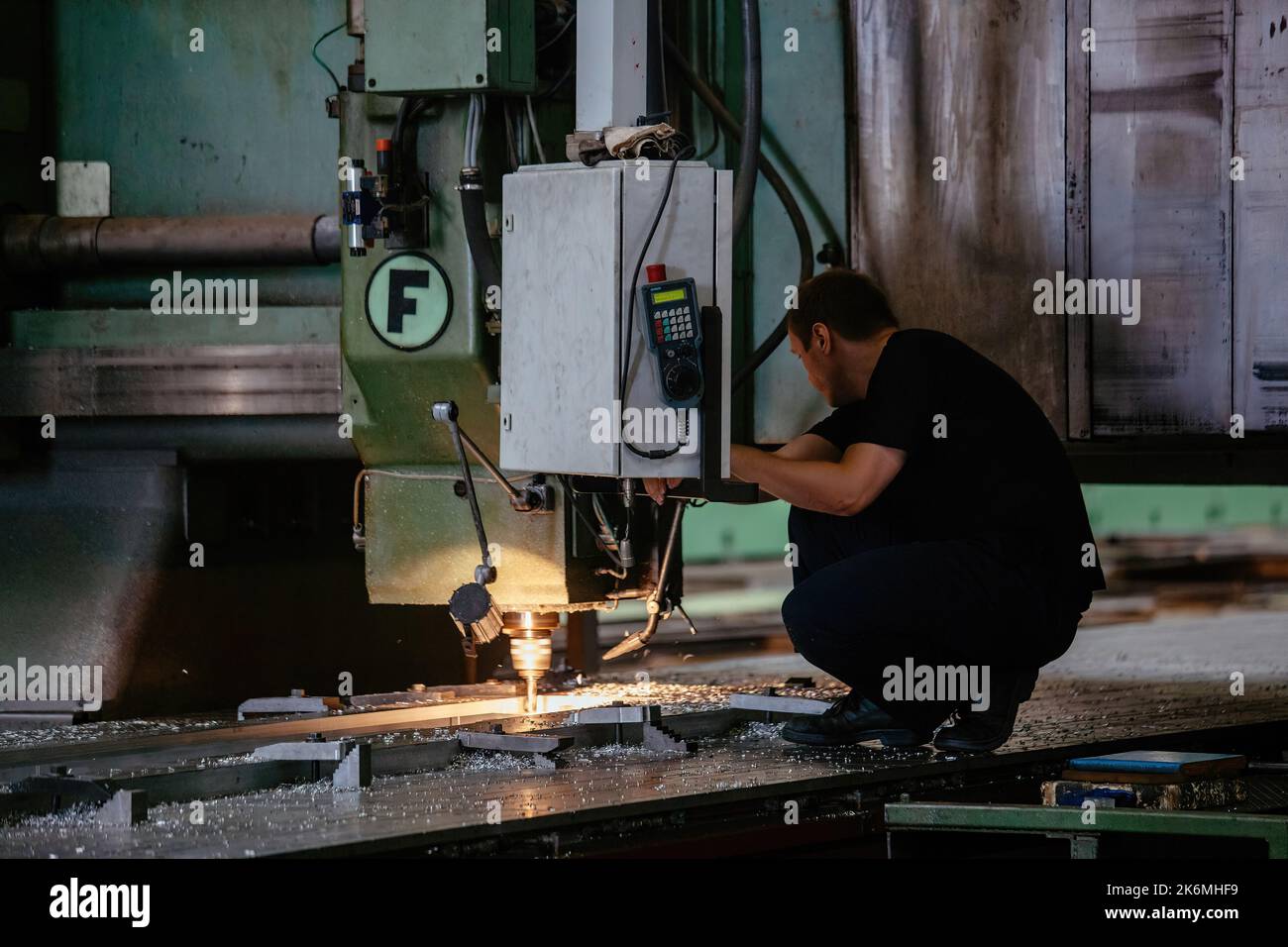 Worker operates drilling machine in factory workshop Stock Photo - Alamy