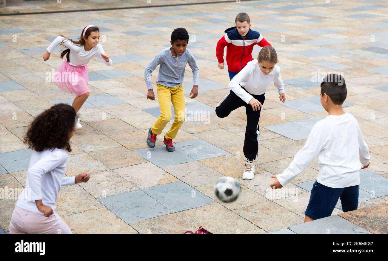 Happy tween girls and boys playing football in schoolyard Stock Photo ...