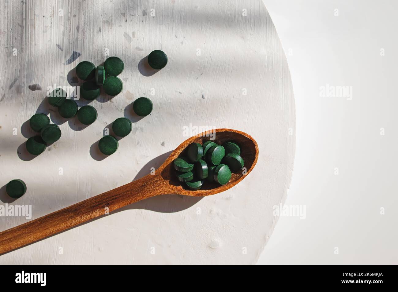 Green tablets in the wooden spoon, spirulina or chlorella food ...