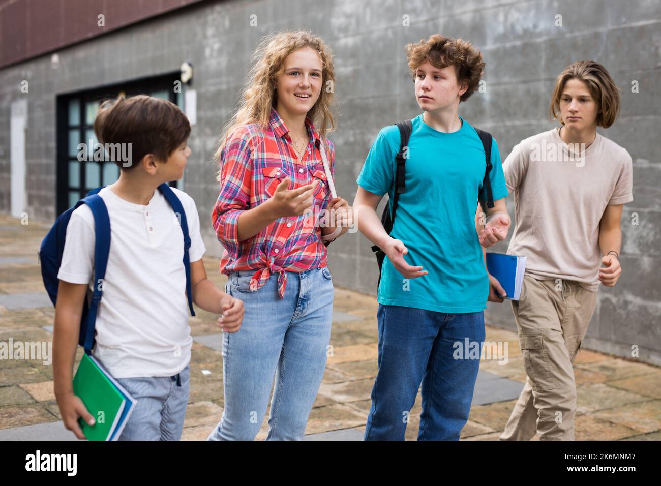 Four teenagers talking about play on walk in street Stock Photo - Alamy