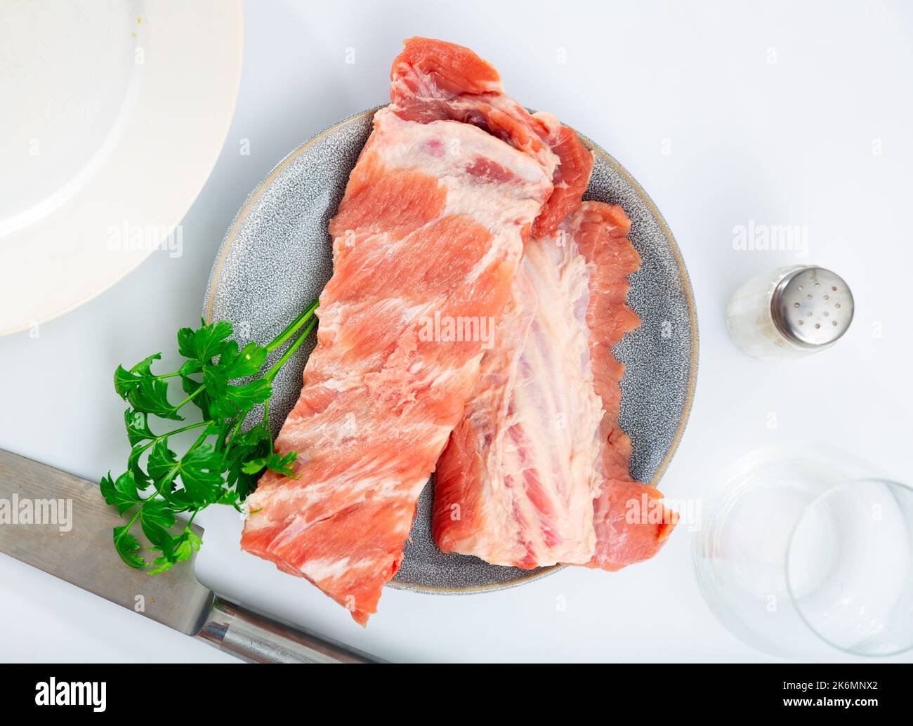 Raw meaty pork ribs slabs on plate with fresh greens Stock Photo - Alamy